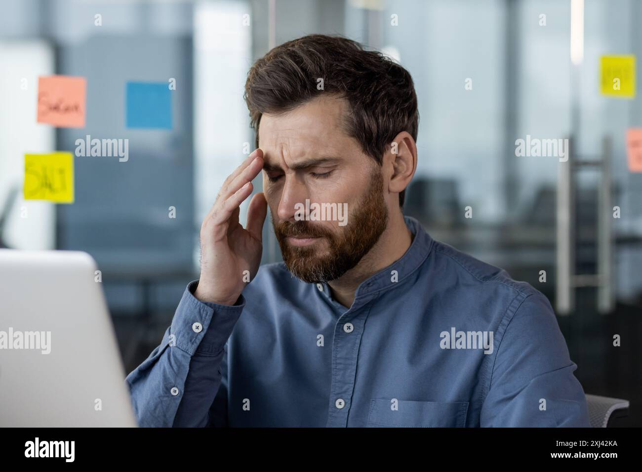 Frustrated businessman sitting in front of computer in modern office ...