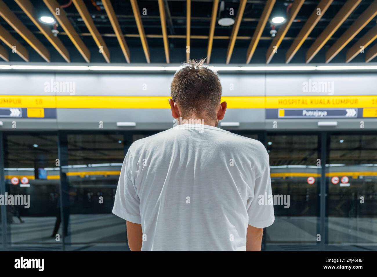 Back view of tired man sit in empty hall of metro station waiting for ...