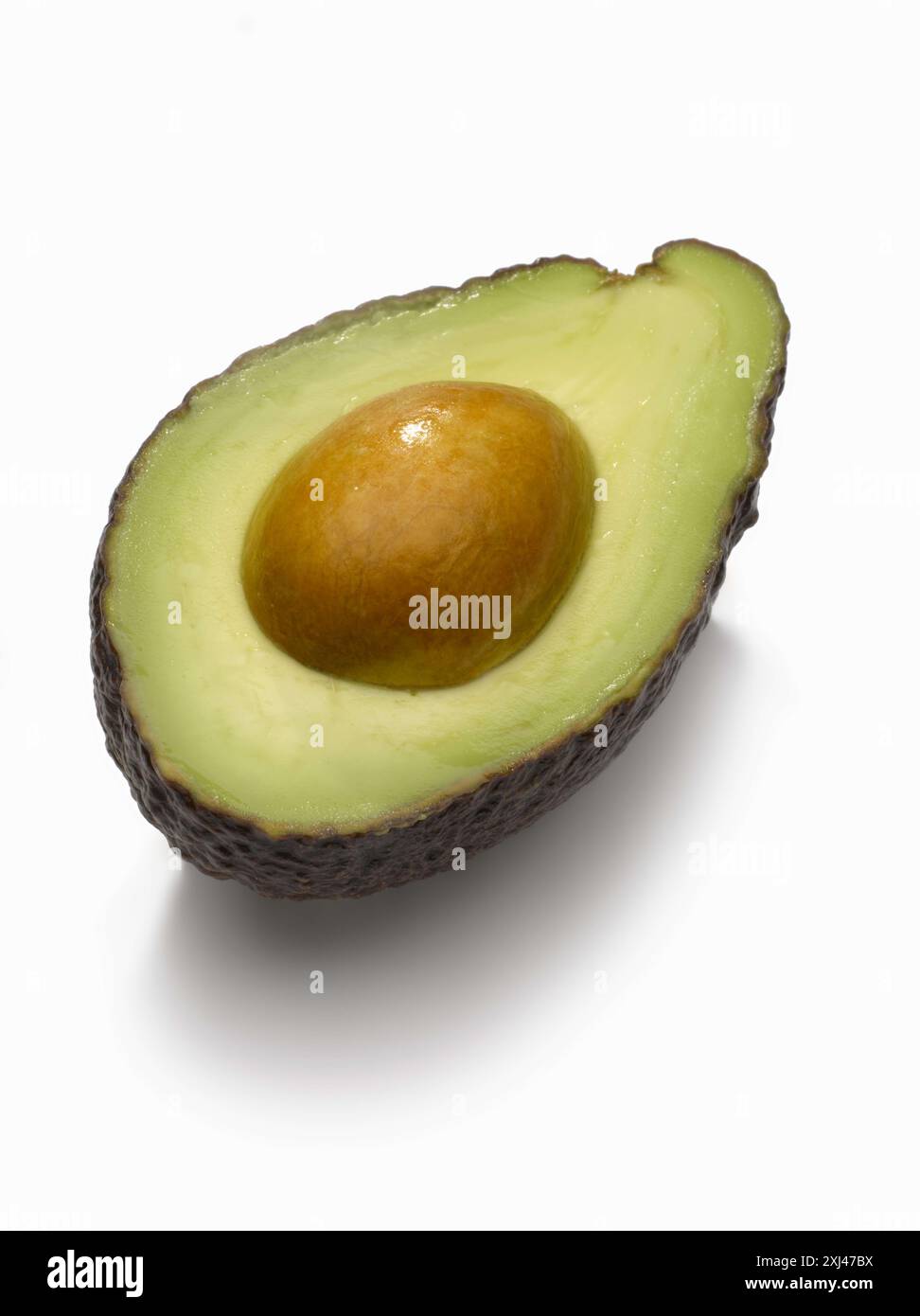 Half avocado and pit Stock Photo - Alamy