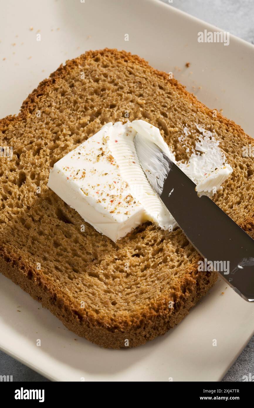 spreading a square of fromage frais on a slice of wholemeal bread Stock ...