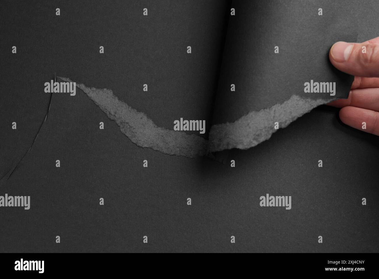 Tearing a black paper sheet with ragged edges. Torn dark grey layered ...