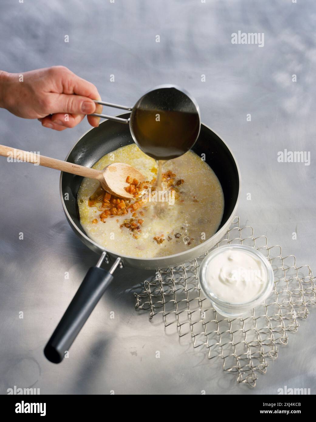 Adding the stock to the vegetables and the cream Stock Photo - Alamy