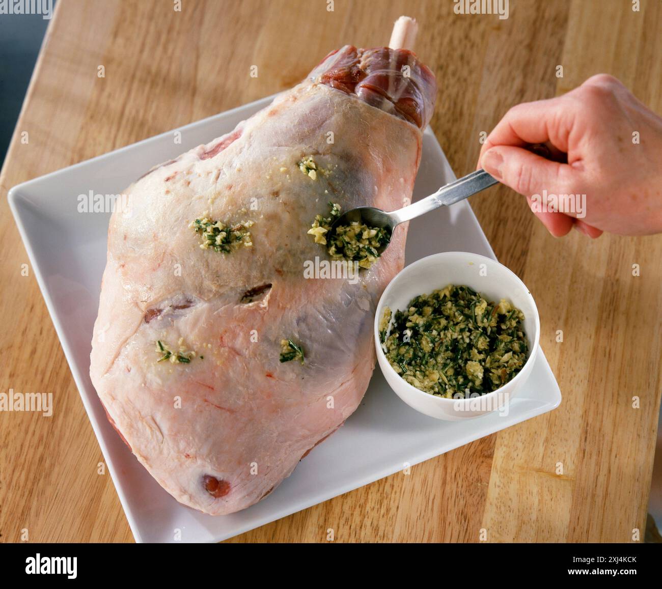 filling the small holes cut in the leg of the lamb with the garlic and ...
