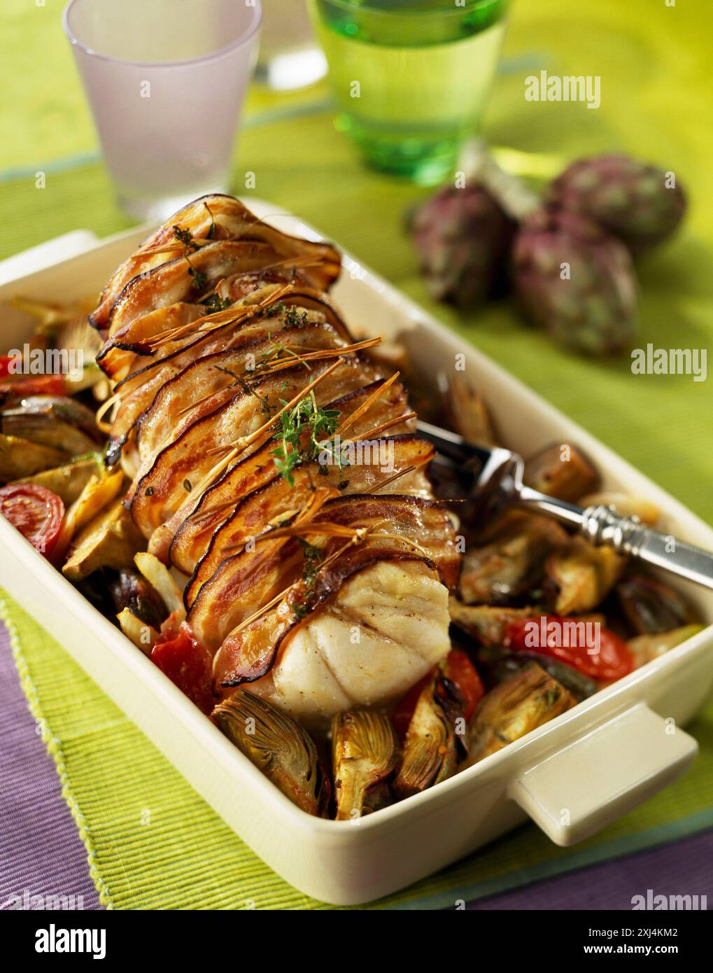 Roast monkfish wrapped in bacon with artichokes Stock Photo - Alamy