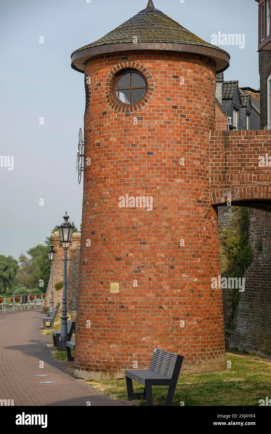 A brick tower with a round window and a lantern in the sun on a path ...
