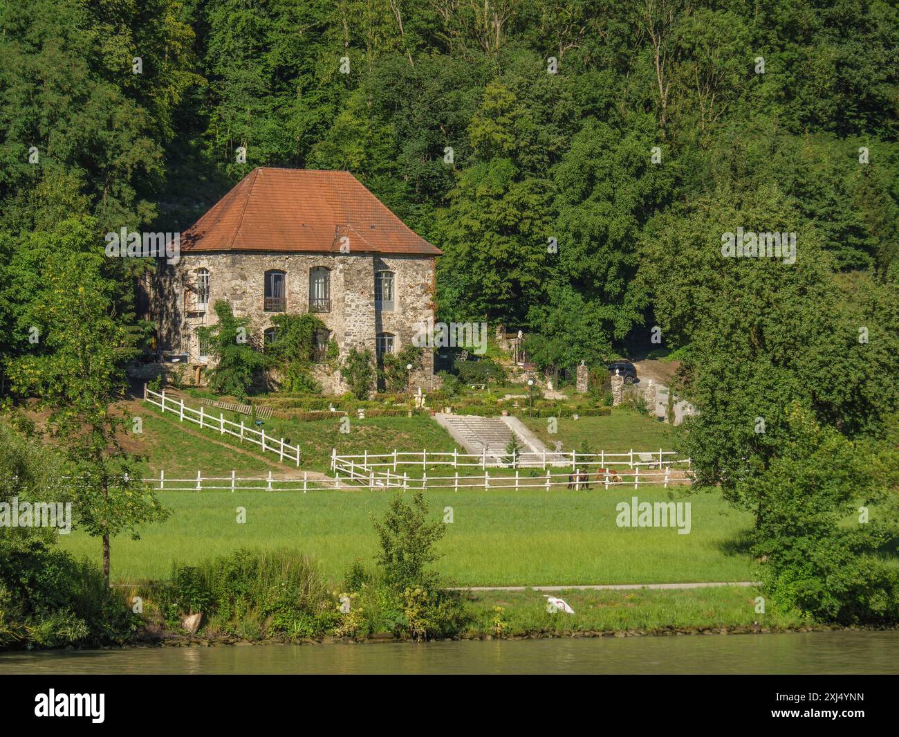 Old stone house with tiled roof, nestled in a green rural landscape ...