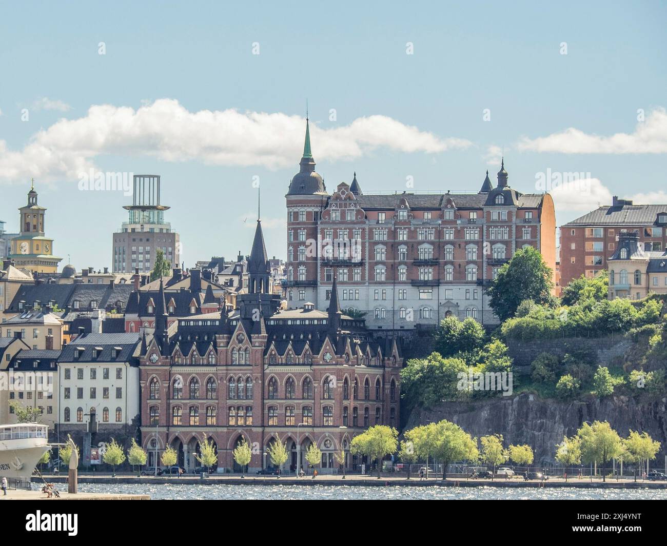 Historic buildings with modern structures behind them and green slopes ...