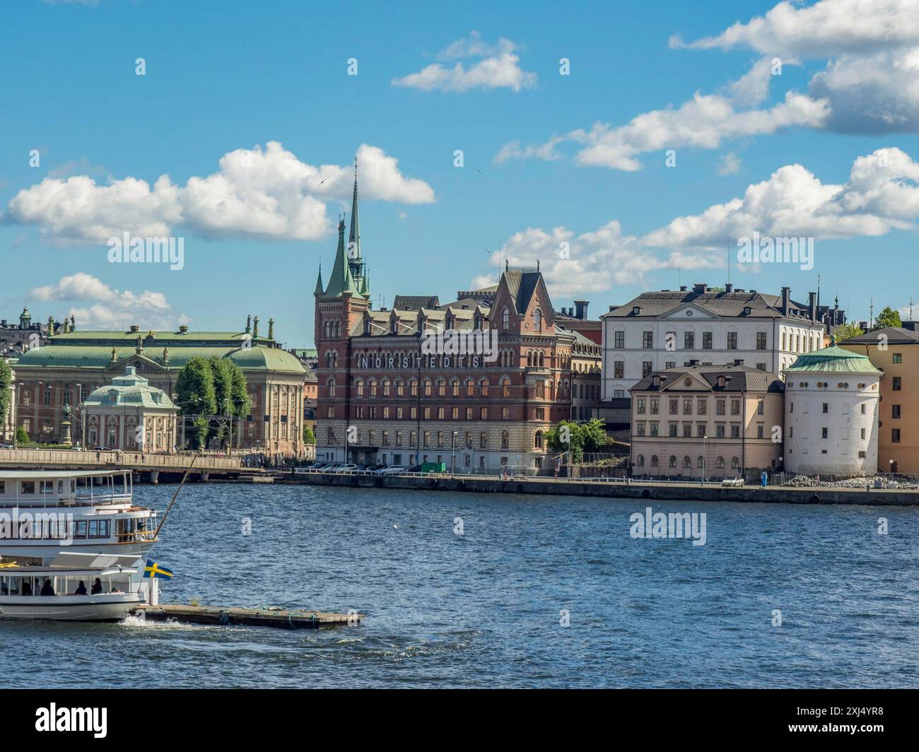 Urban architecture along the water with a boat and blue sky with clouds ...