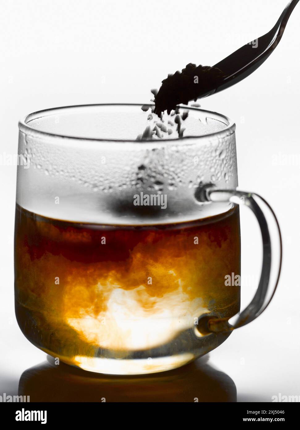 Adding the instant coffee to a cup of boiling hot water Stock Photo - Alamy