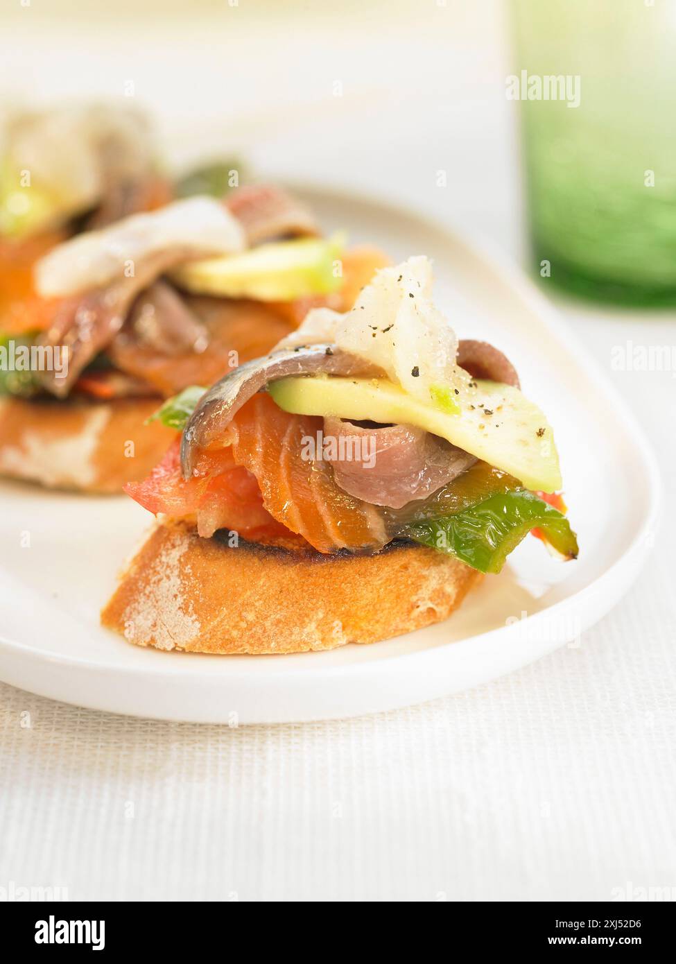 Smoked fish and grilled green peppers on a bite-size slice of bread ...