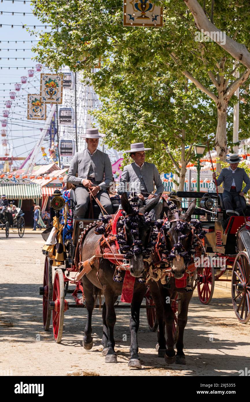 Men in hats driving a horse-drawn carriage down a tree-lined street ...