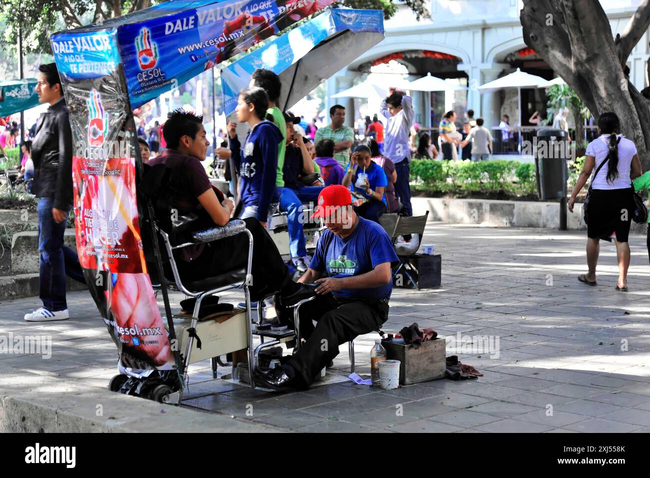 Oaxaca, Mexico, Central America, A shoeshine boy works on a pavement ...