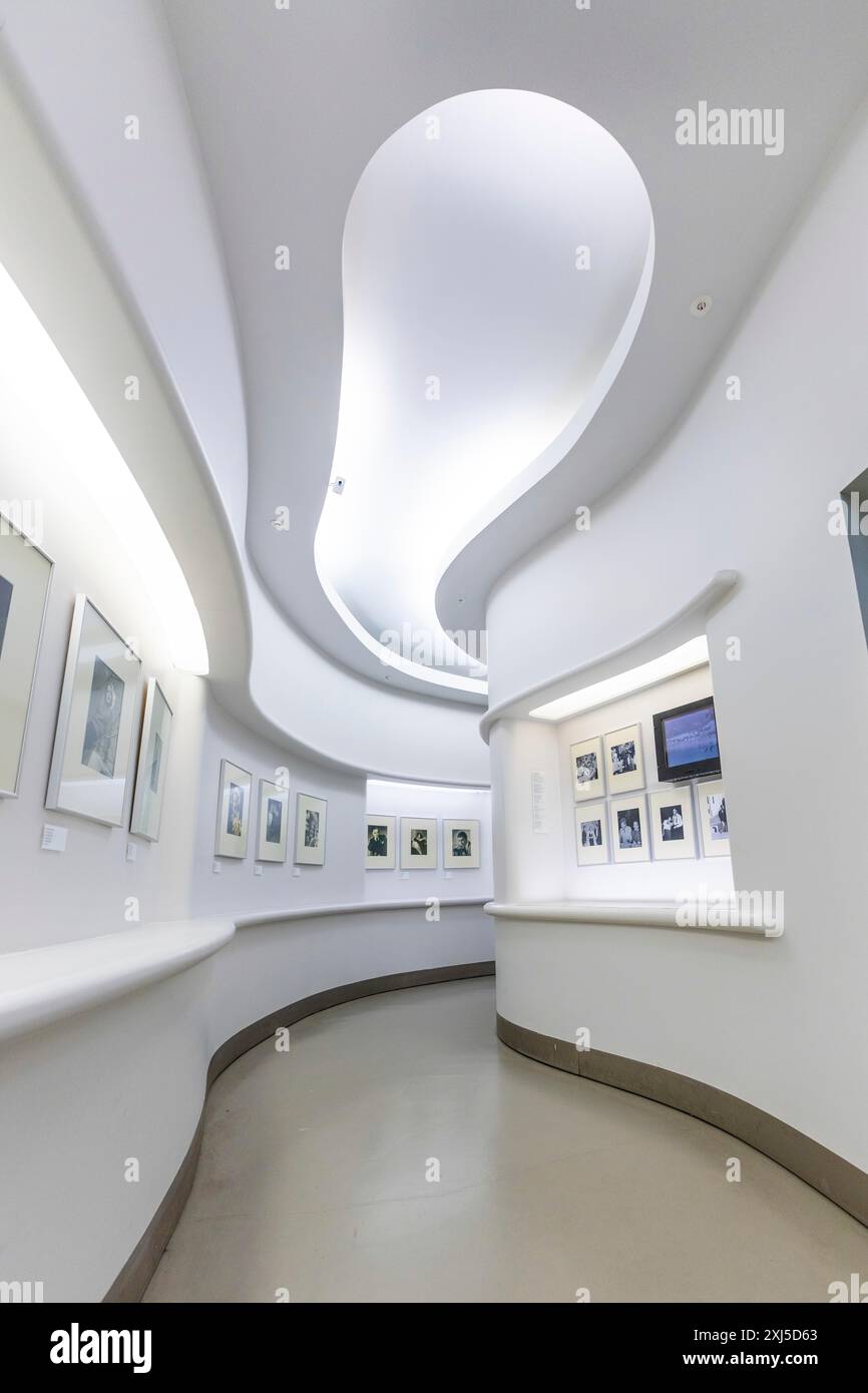 Bright, minimalist exhibition space with undulating white walls and ...