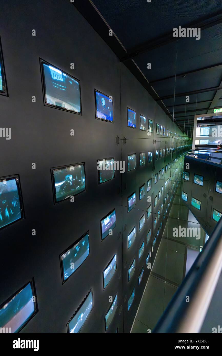 Dark, modern showroom with numerous illuminated screens on the walls ...