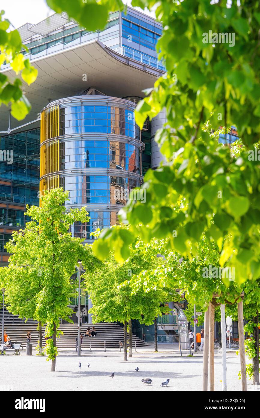 Modern building with glass facade and yellow accents, surrounded by ...