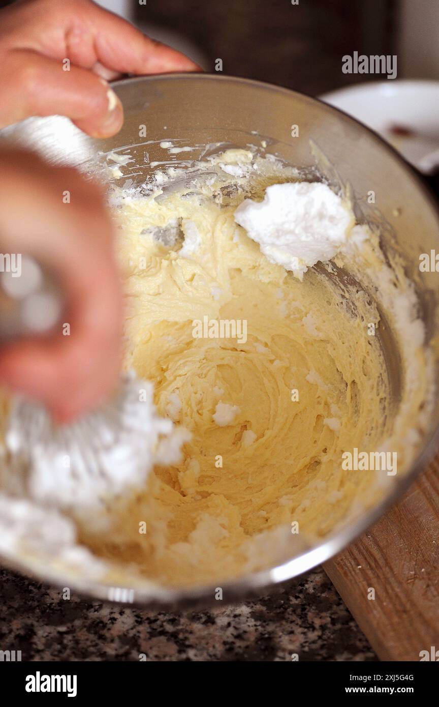 Adding the beaten egg whites to the cake preparation Stock Photo - Alamy
