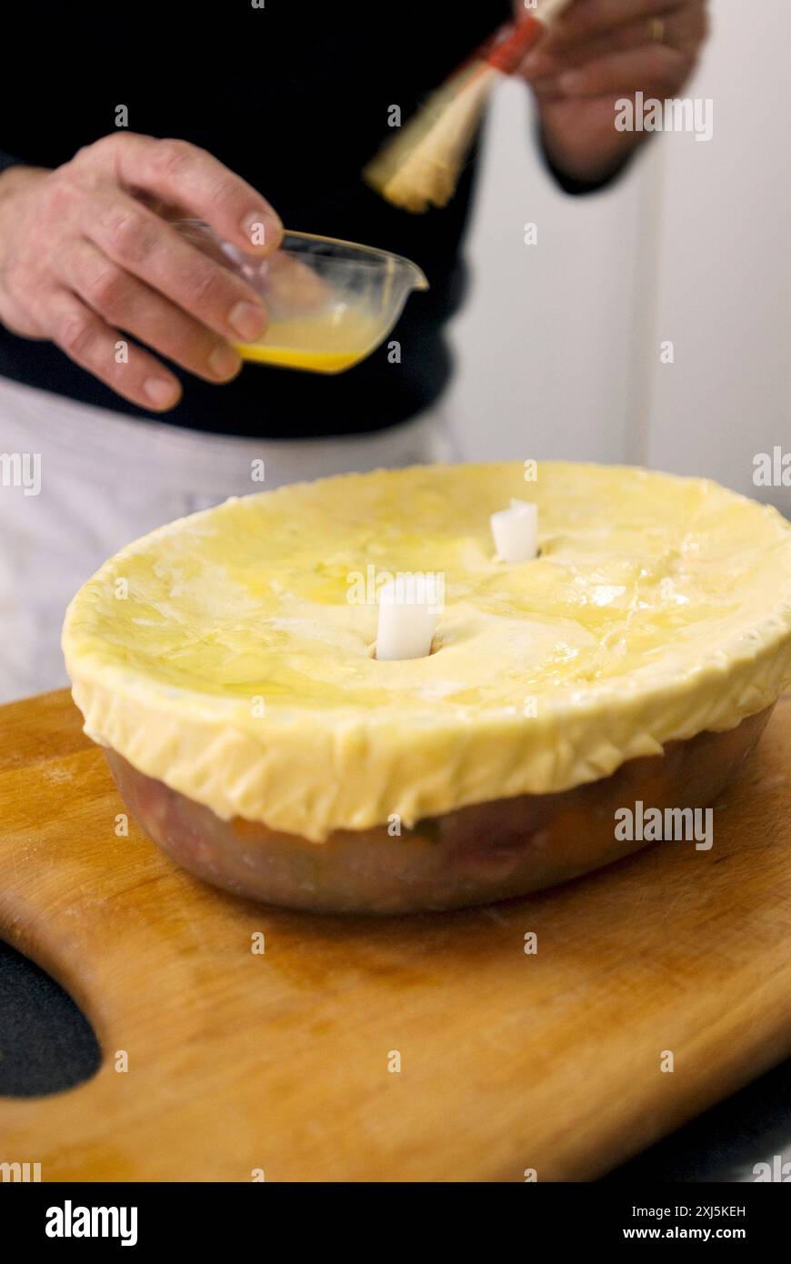 Coating the pastry with a beaten egg yolk Stock Photo - Alamy