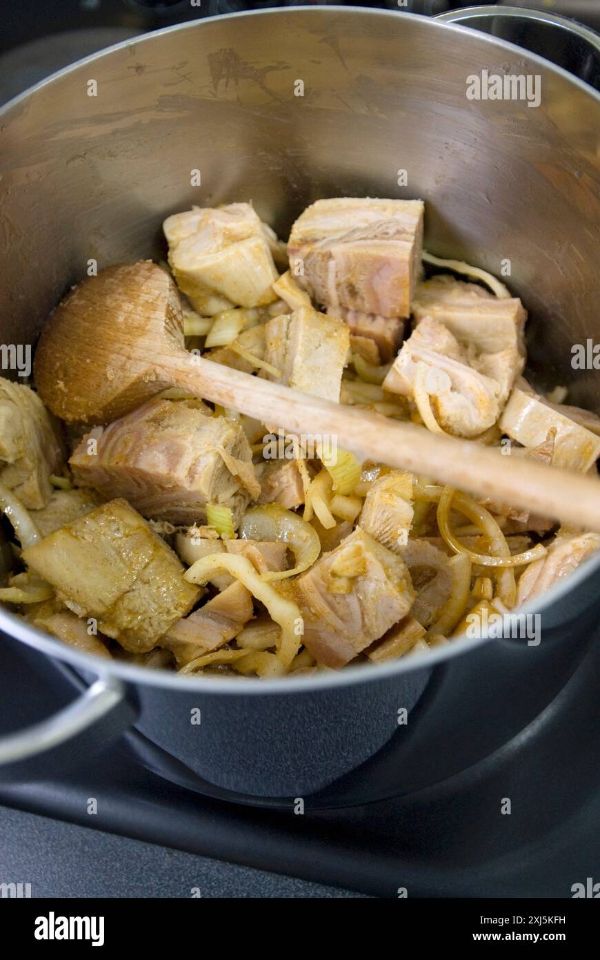 Adding the tripe cubes to the onions in the stewpot Stock Photo - Alamy