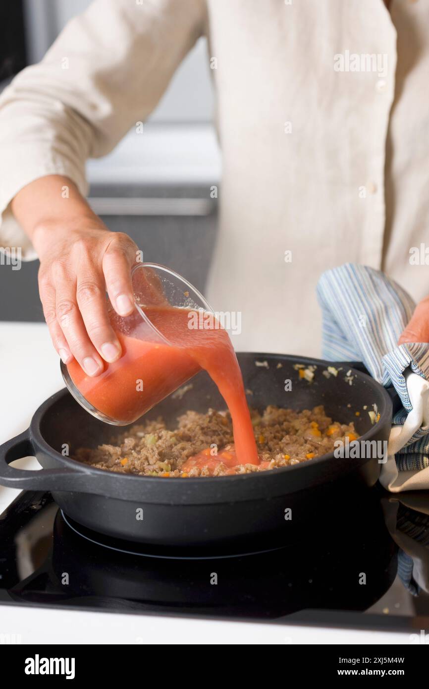 Adding the tomato sauce to the preparation Stock Photo - Alamy