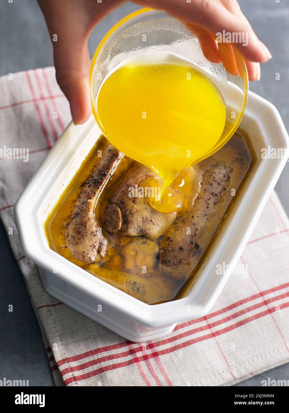 Covering the goose foie gras with the melted grease before putting in ...