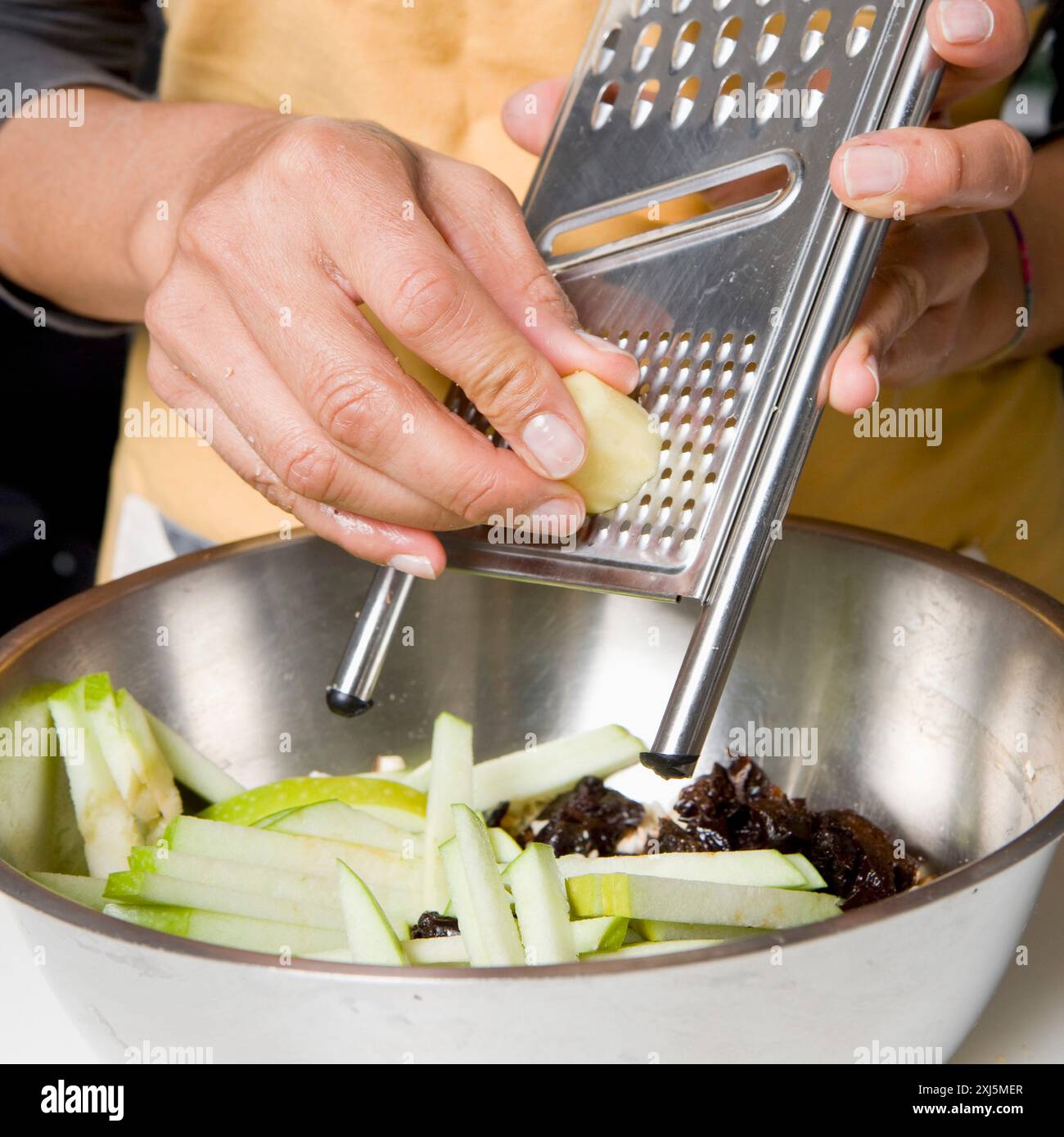 Grating the ginger into the bowl of apples and prunes Stock Photo - Alamy