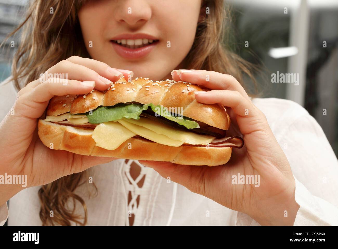 Woman eating a turkey ham,cheese and vegetable milkbread sandwich Stock ...