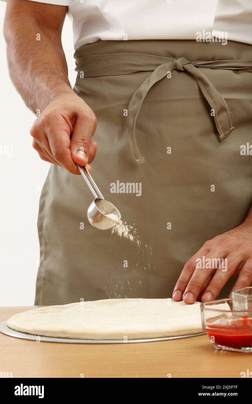 Sprinkling flour over a circle of raw pastry Stock Photo - Alamy