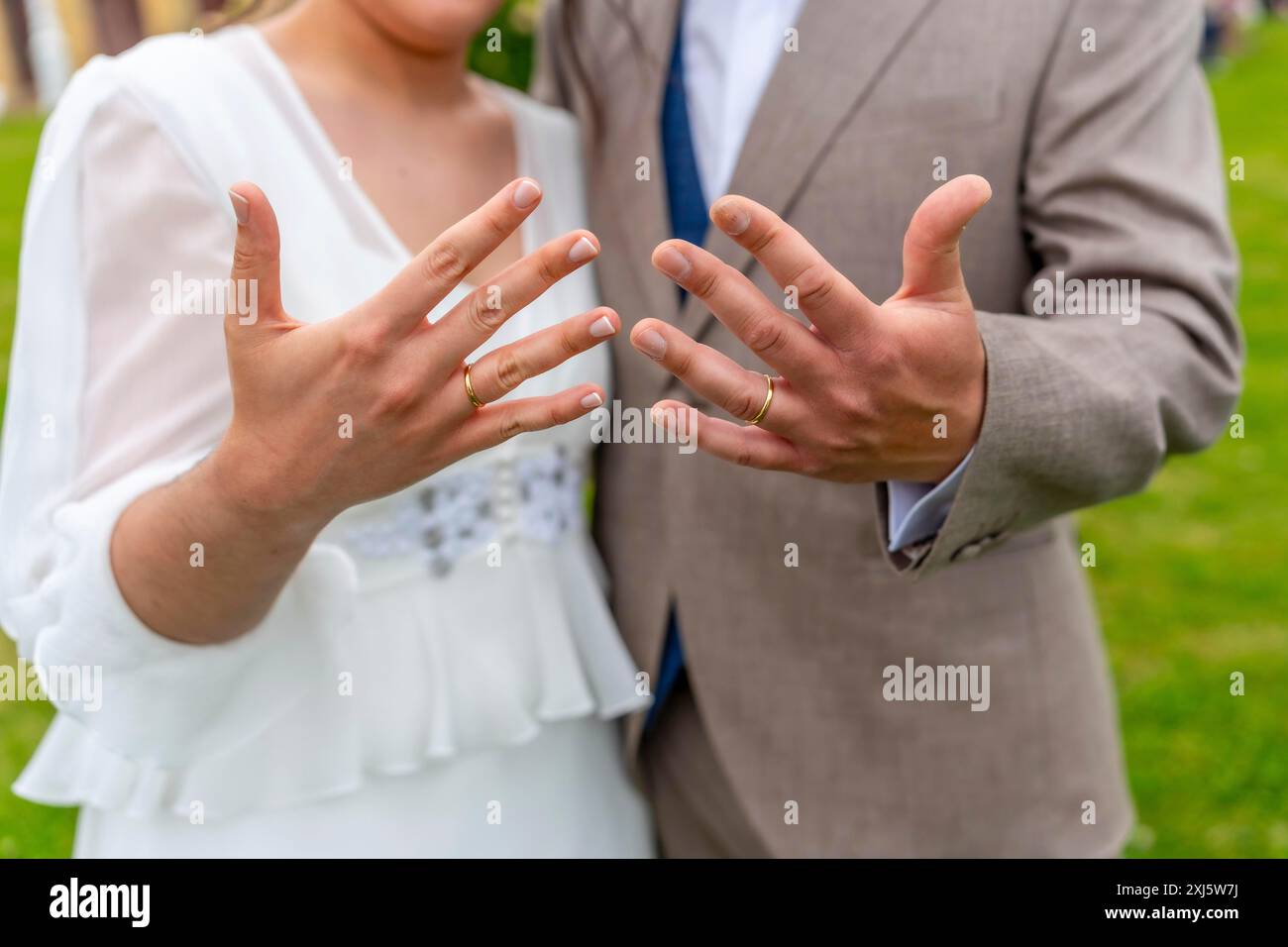 A couple is posing for a picture with their wedding rings. The man is ...