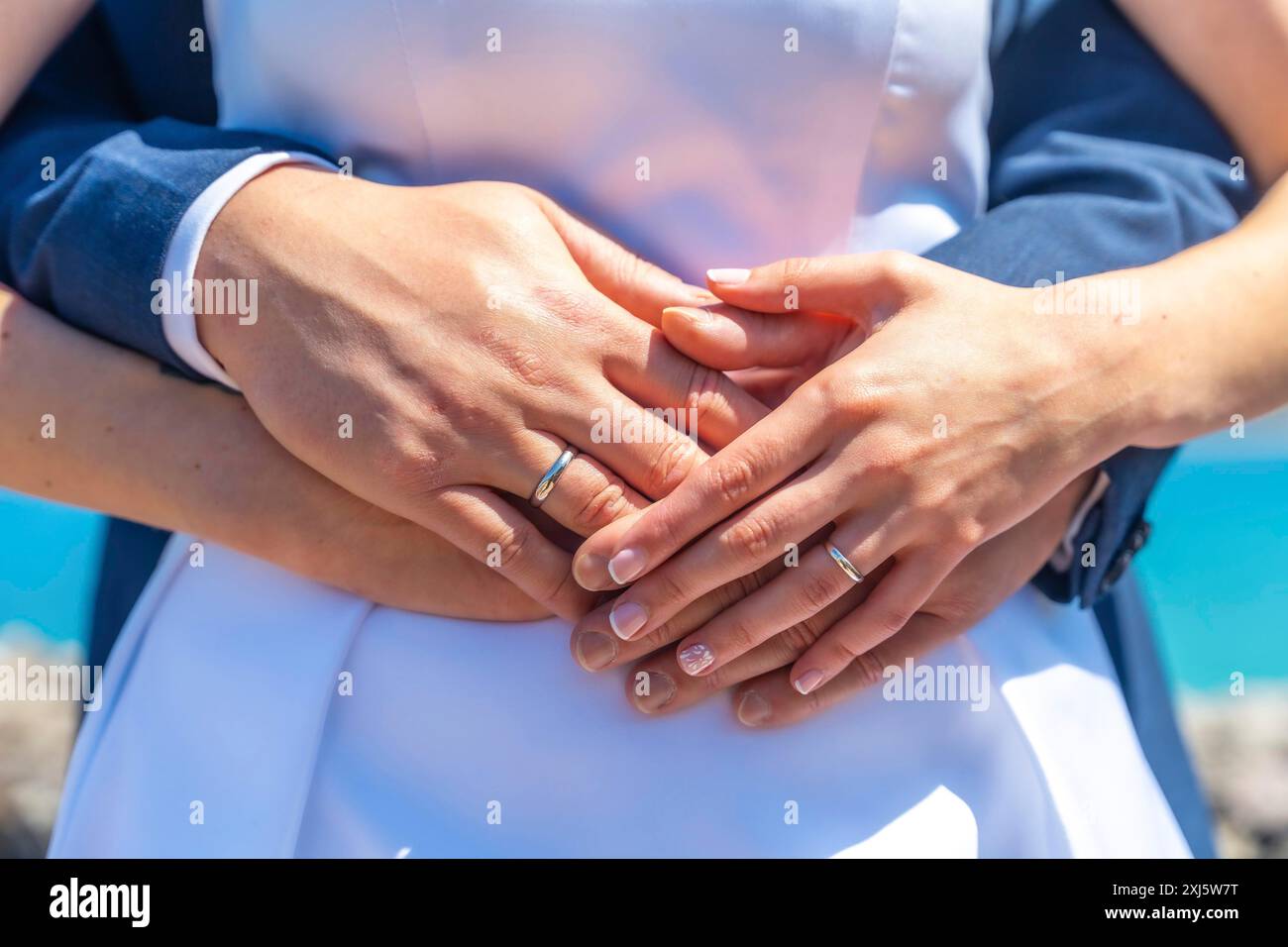 A couple is holding hands and wearing wedding rings. The woman is ...
