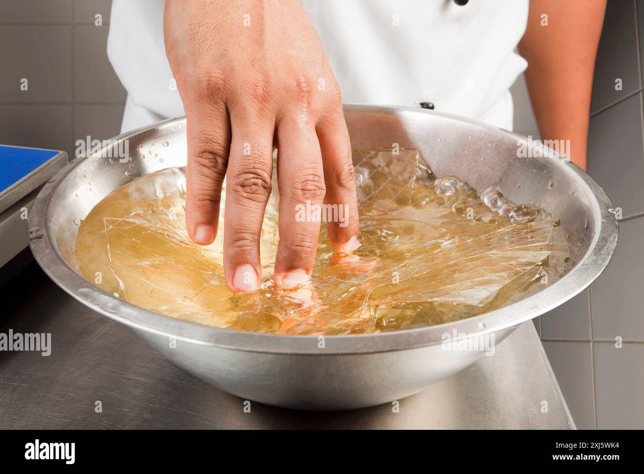 Soaking the gelatine leaves in a bowl of water Stock Photo - Alamy