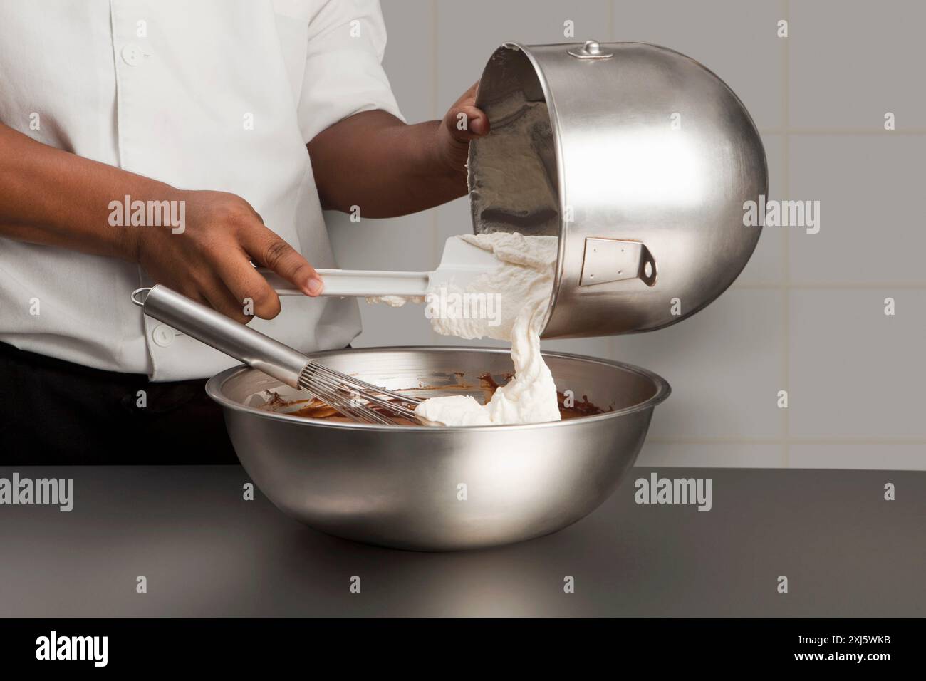Cook adding the whipped egg whites to the melted chocolate Stock Photo ...