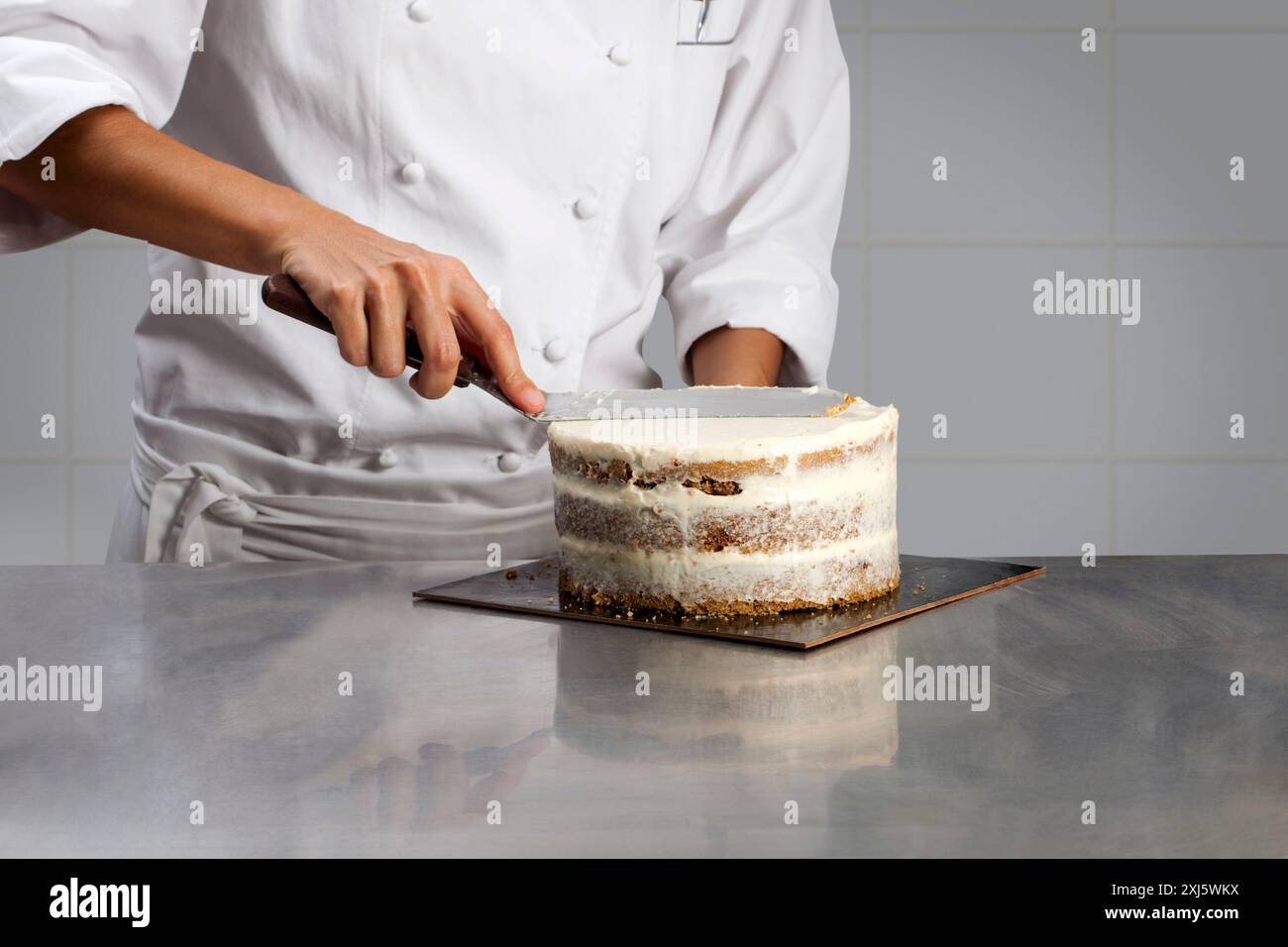 Cook coating a cake with cream Stock Photo - Alamy