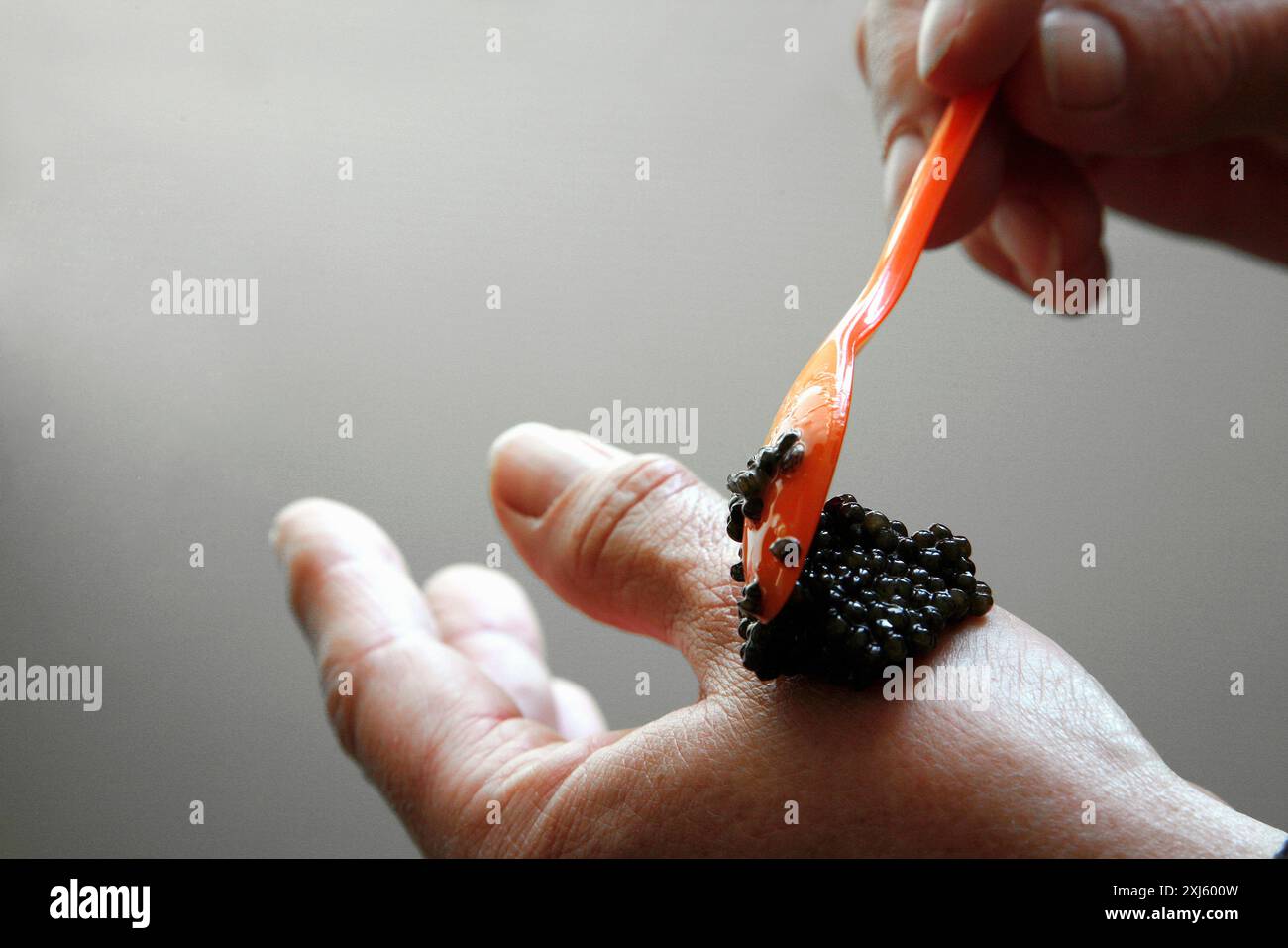Placing a spoonful of caviar on a hand to taste Stock Photo - Alamy