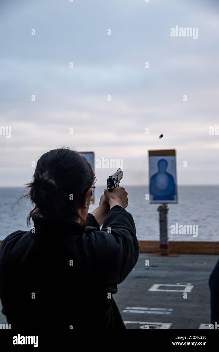 A Sailor fires an M9 service pistol during a small arms live-fire ...