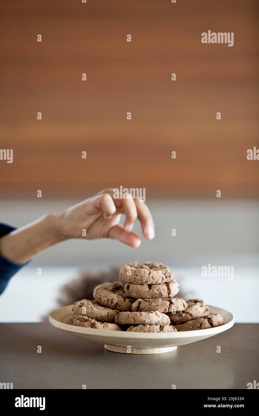 Child's hand stealing a cookie from a plate of cookies Stock Photo - Alamy