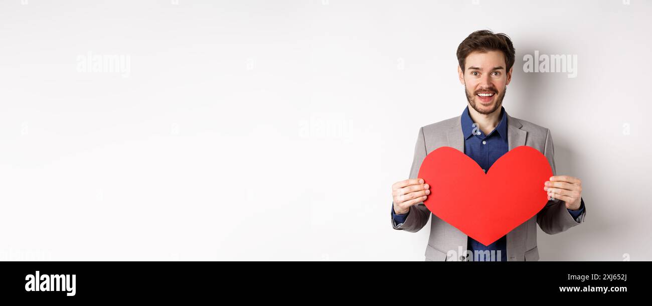 Happy man confessing in love, showing heart cutout and smiling at ...