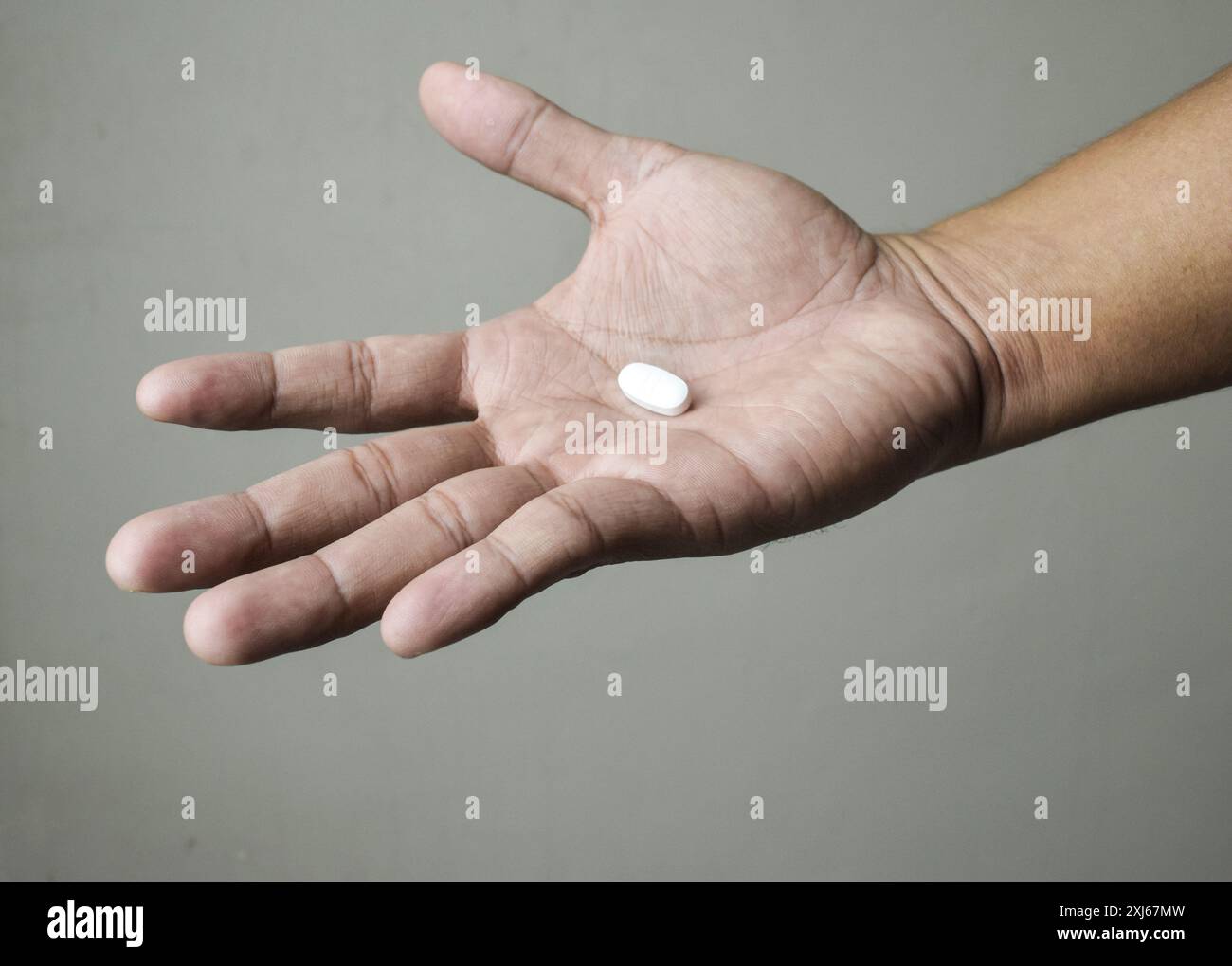 A white gray pill in the form of a capsule lies in an outstretched male ...