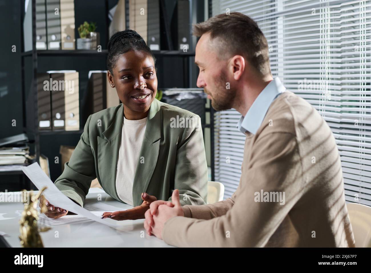 Confident African American female solicitor looking at male client and ...