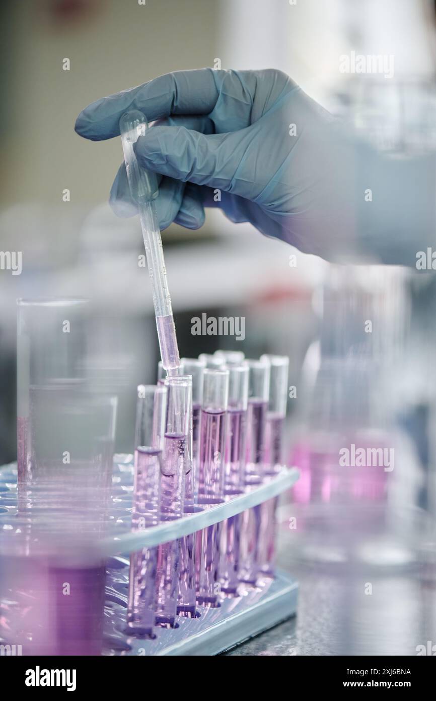 Gloved hand of modern clinician or researcher dropping liquid substance ...