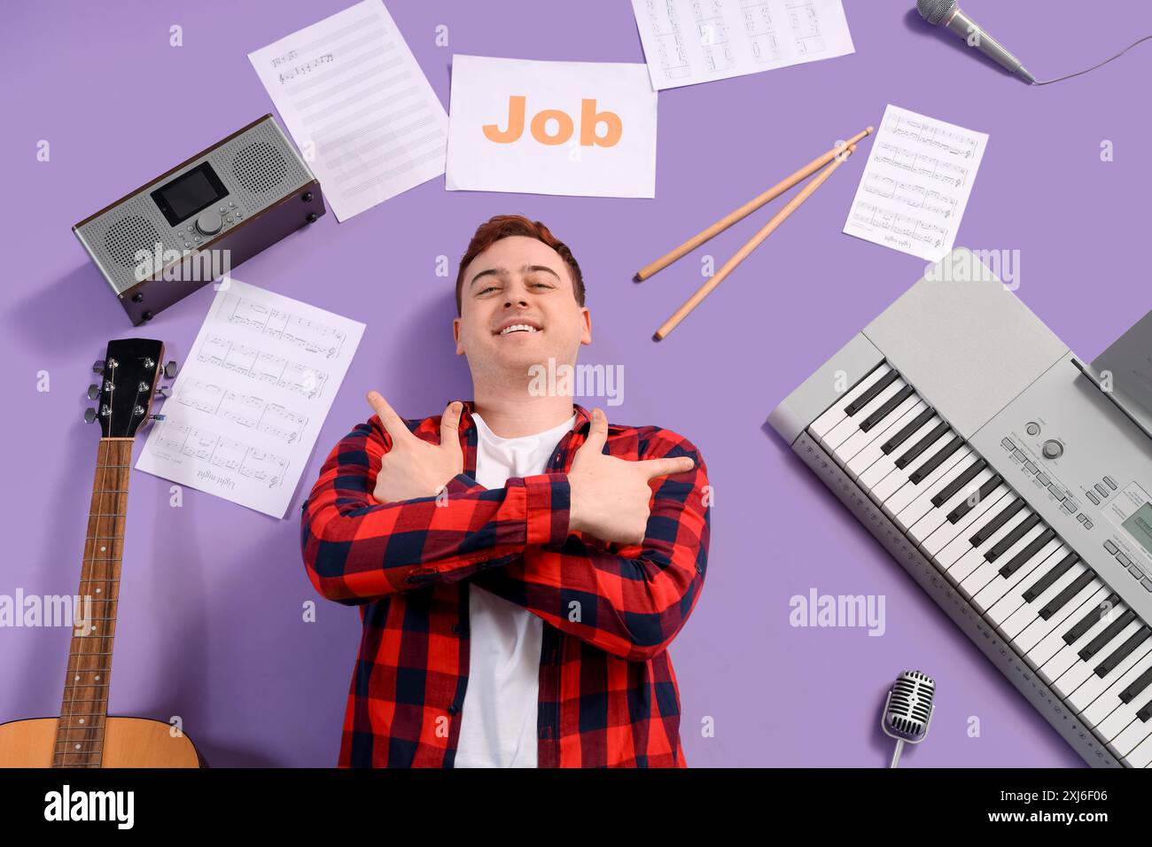 Male artist with musical instruments, note sheets and word JOB on lilac ...
