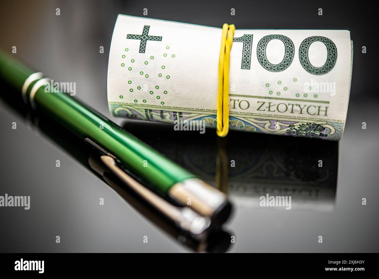A close-up image showing a rolled 100 Polish Zlotys note secured with a ...