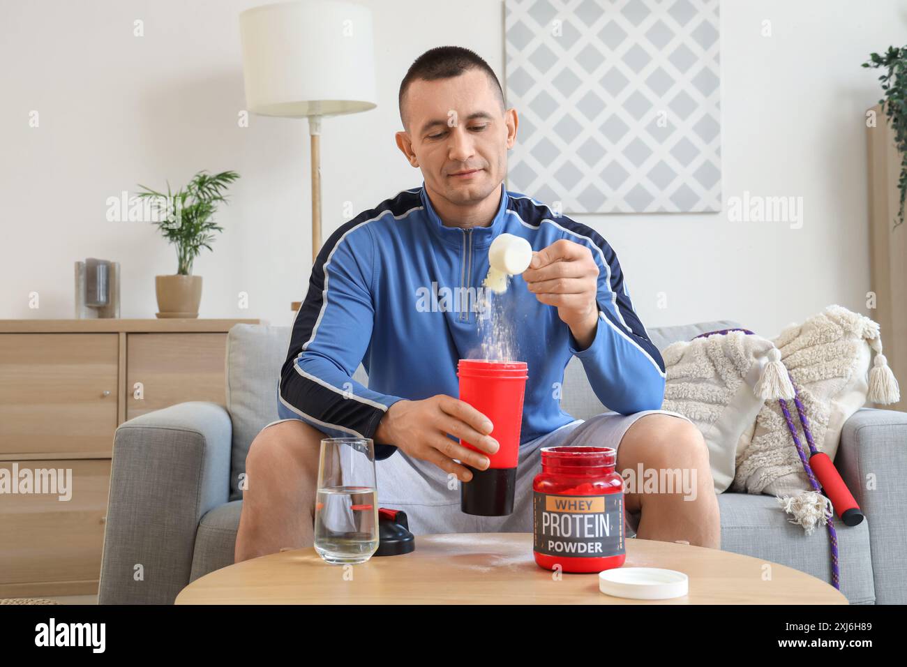 Sporty young man pouring protein powder into bottle at home Stock Photo ...