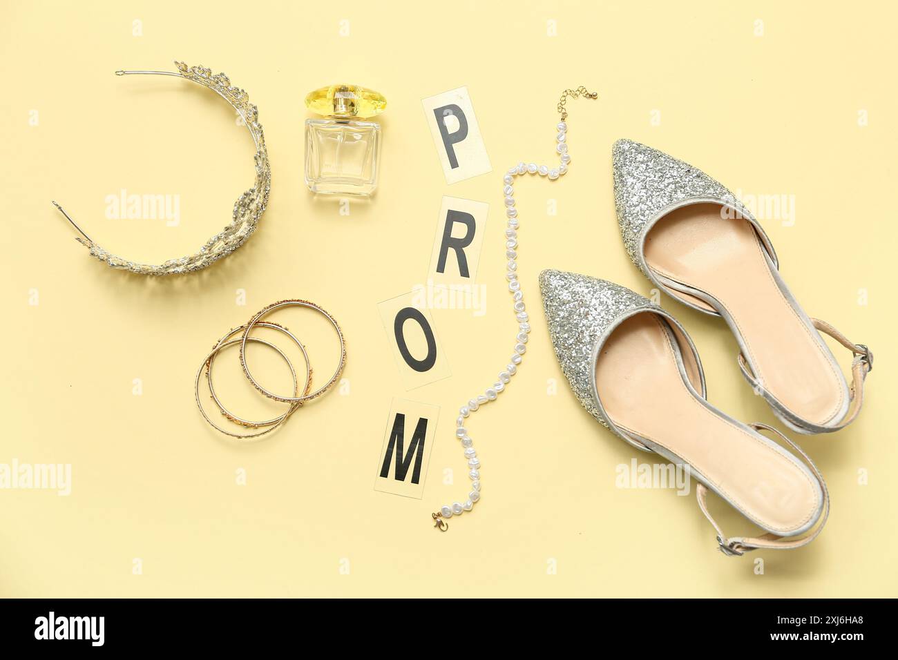 Word PROM with female shoes, tiara and perfume bottle on light yellow ...