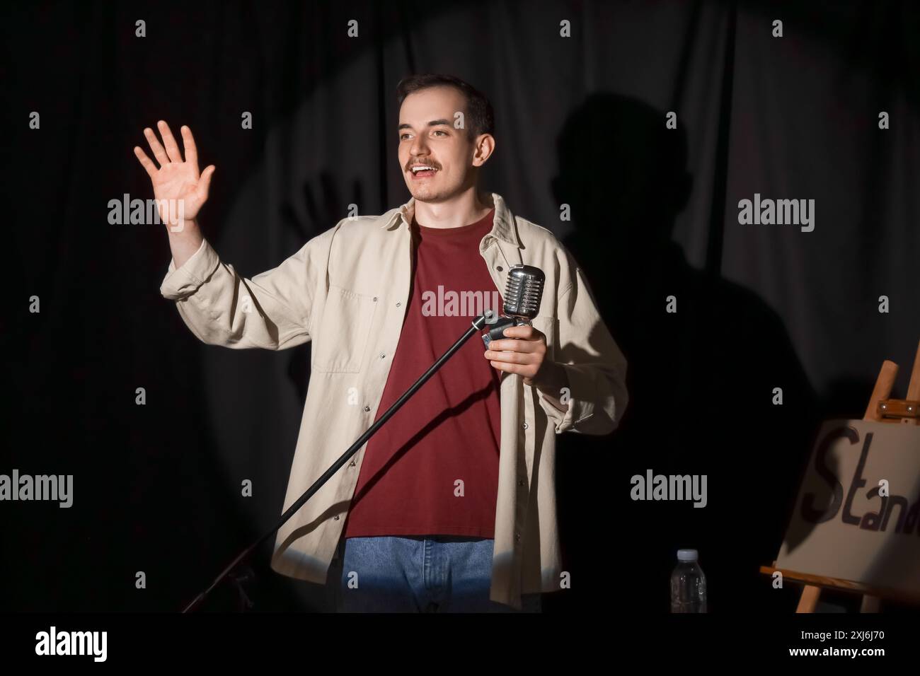 Standup comedian waving hand on stage Stock Photo - Alamy