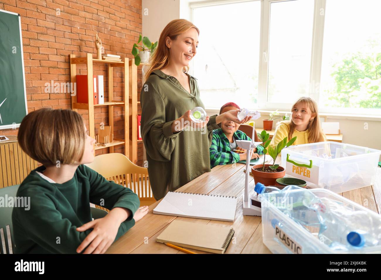 Female teacher with pupils sorting garbage in classroom. Ecology ...