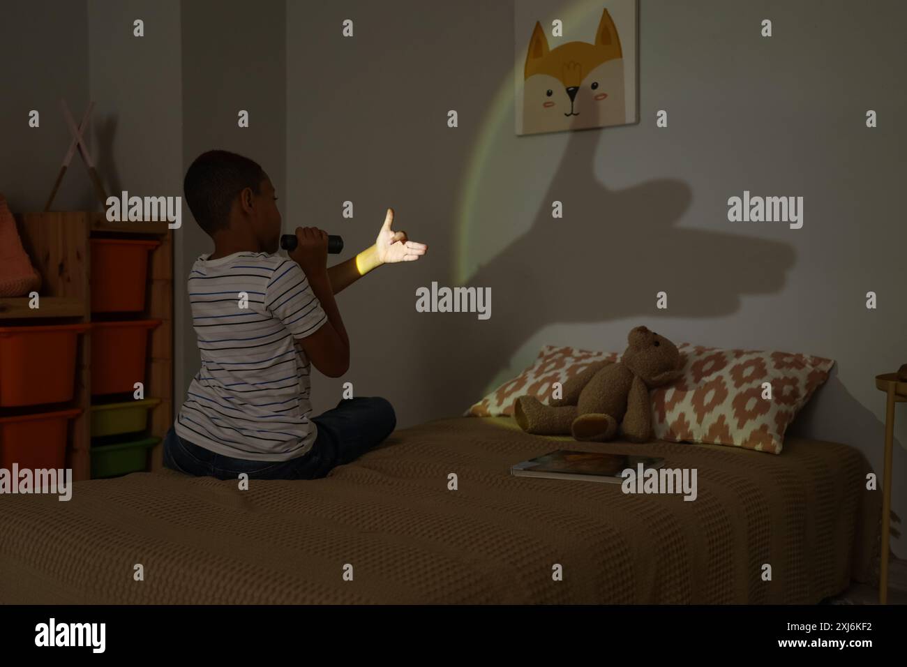 Little boy with flashlight playing shadow in dark bedroom, back view ...