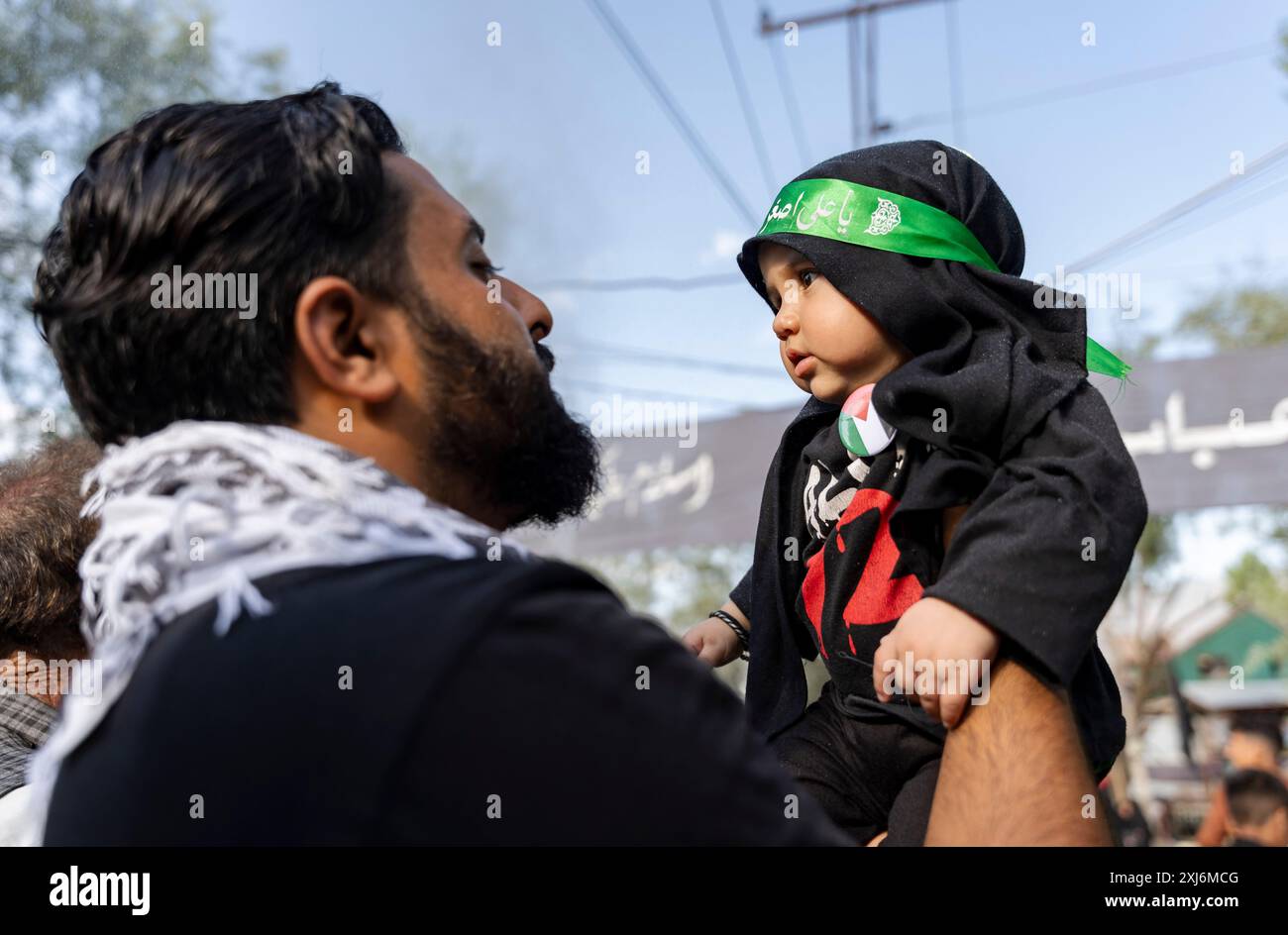 A father holds his kid dressed in religious clothes in his arms during ...