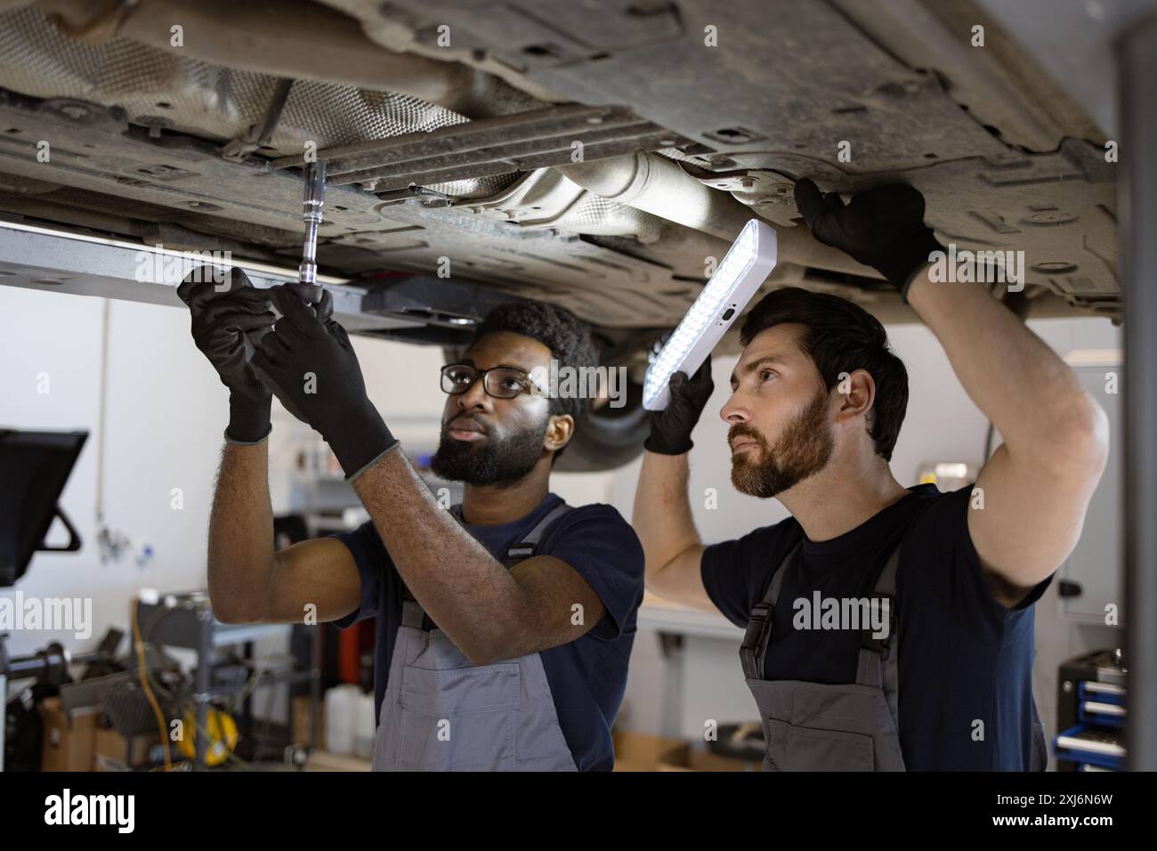 Mechanics working under car in garage workshop Stock Photo - Alamy