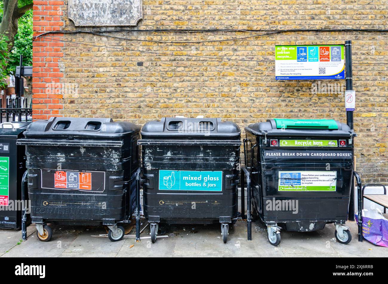 A recycling station with bins for glass, cardboard and plastics on ...
