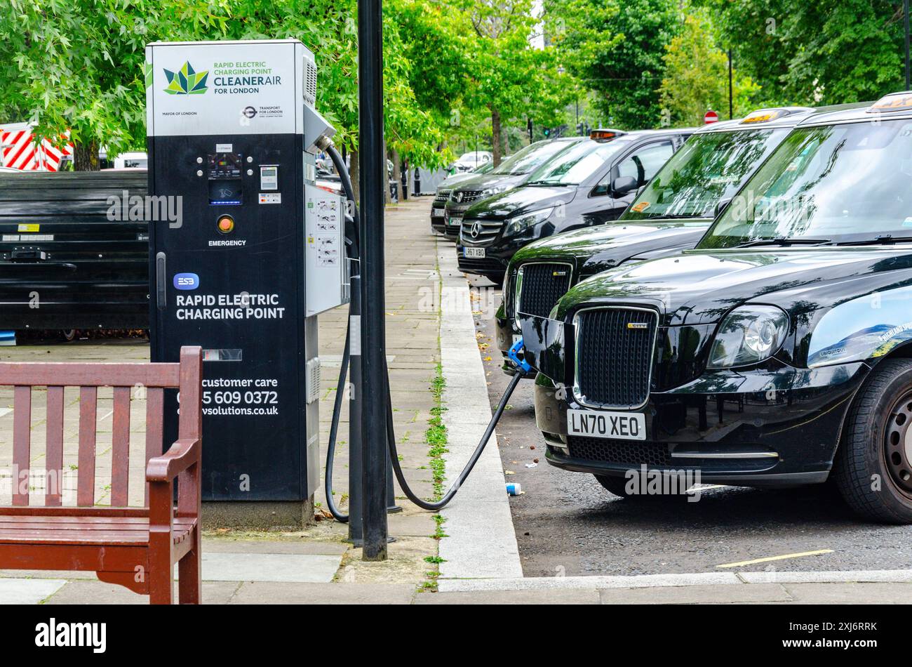 A black, London taxi cab plugged into a rapid electric charging point to charge on Warwick ...